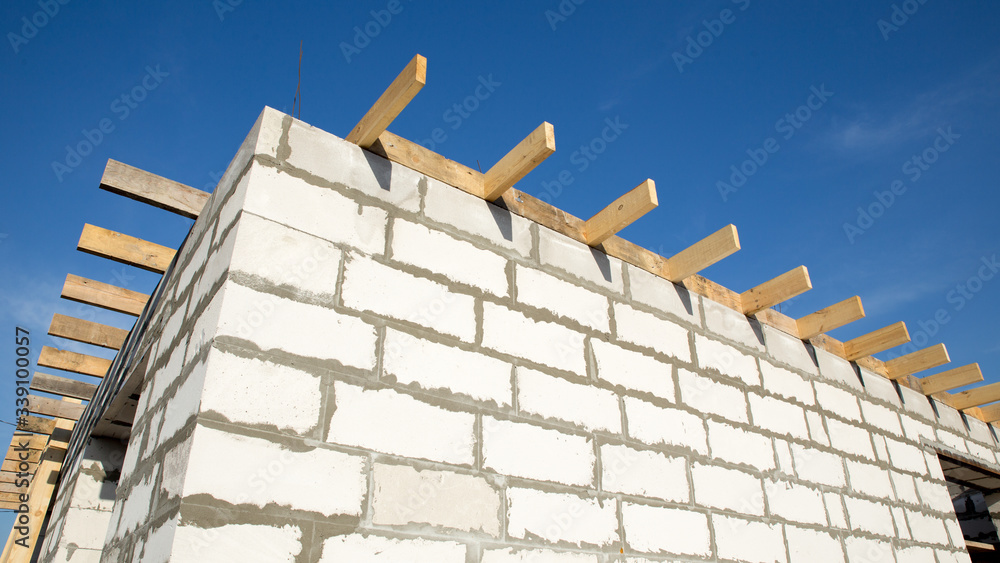 Building site of a house under construction. corner unfinished house walls made from white ...