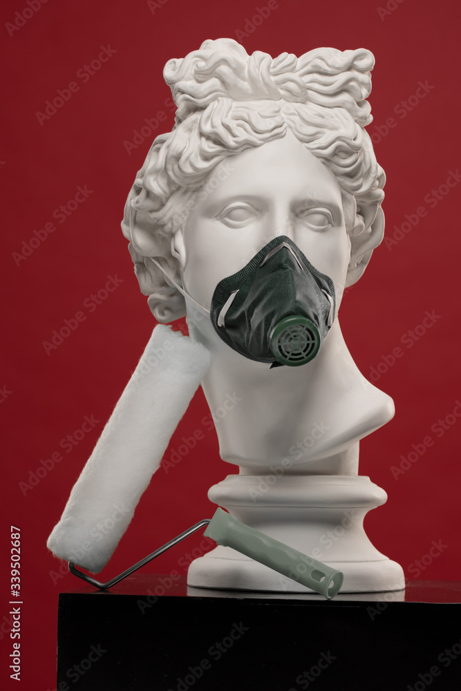White plaster statue of a bust of Apollo Belvedere in a mask respirator ...