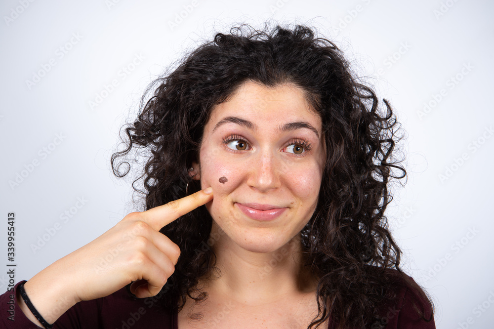 Young pretty caucasian curly haired woman pointing on her face with big ...