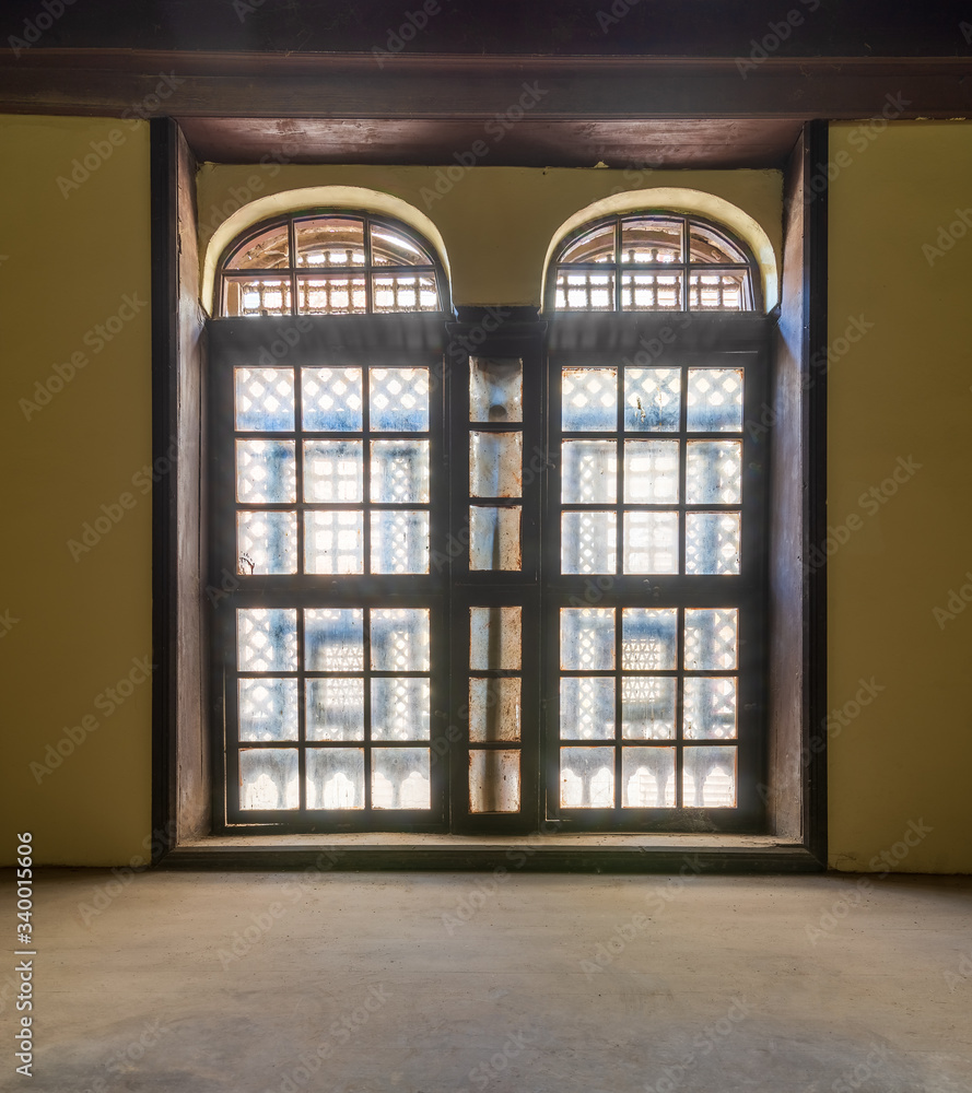 Large vintage window with ornament located inside empty room with ...