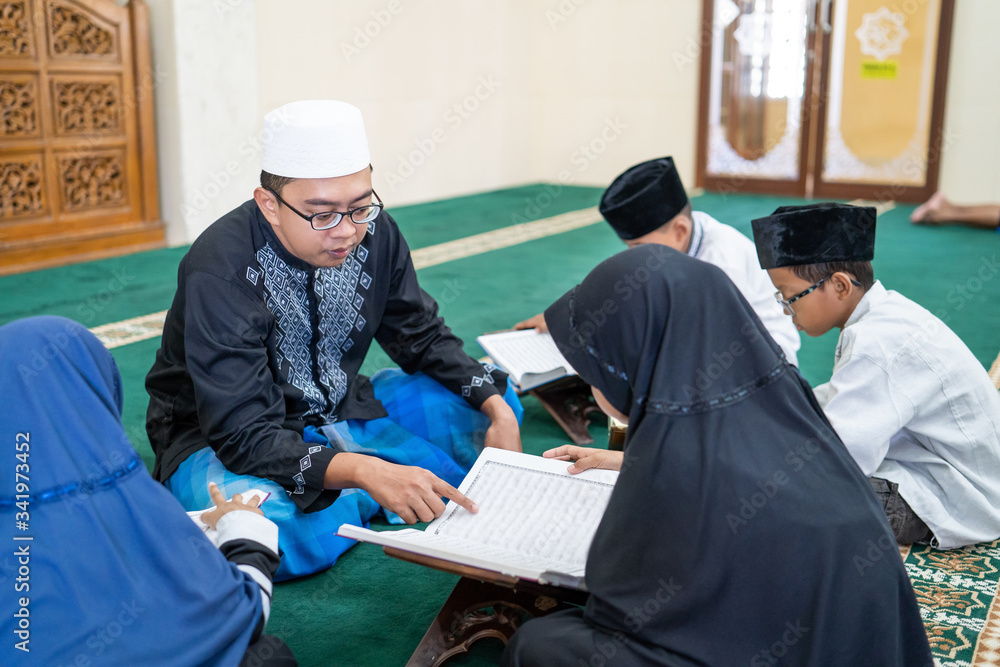 teacher is teaching muslim kid how to read holy quran in the mosque ...