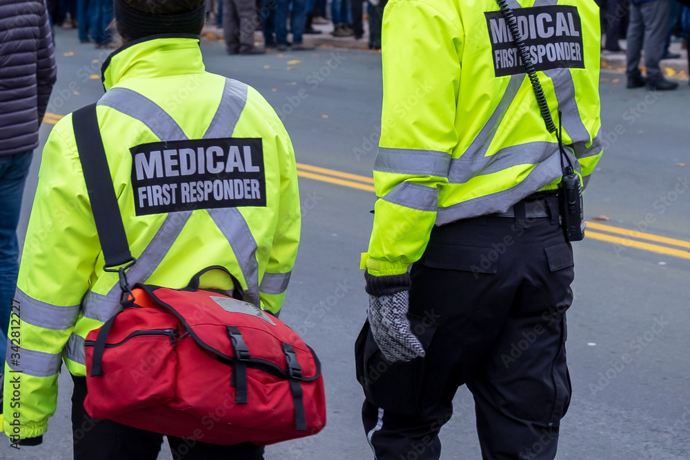Two medical responders walking in a street with bright yellow coats ...