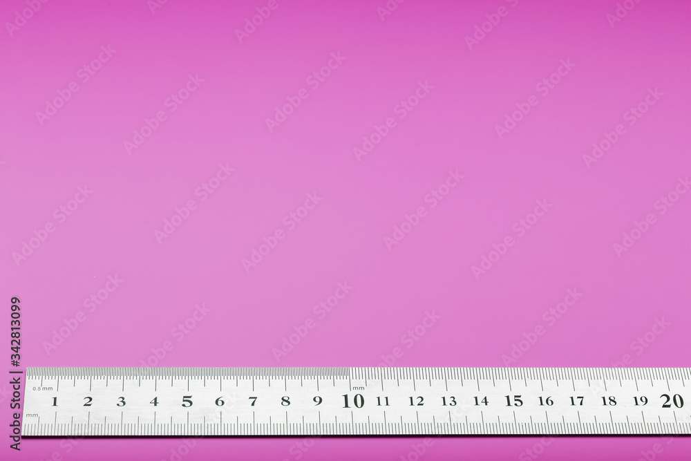 A metal ruler with a scale on a pink background is a superscape with a ...
