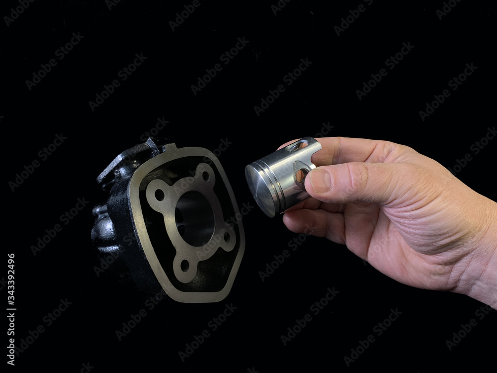 Cylinder and piston in a hand, on a black background. Piston system ...