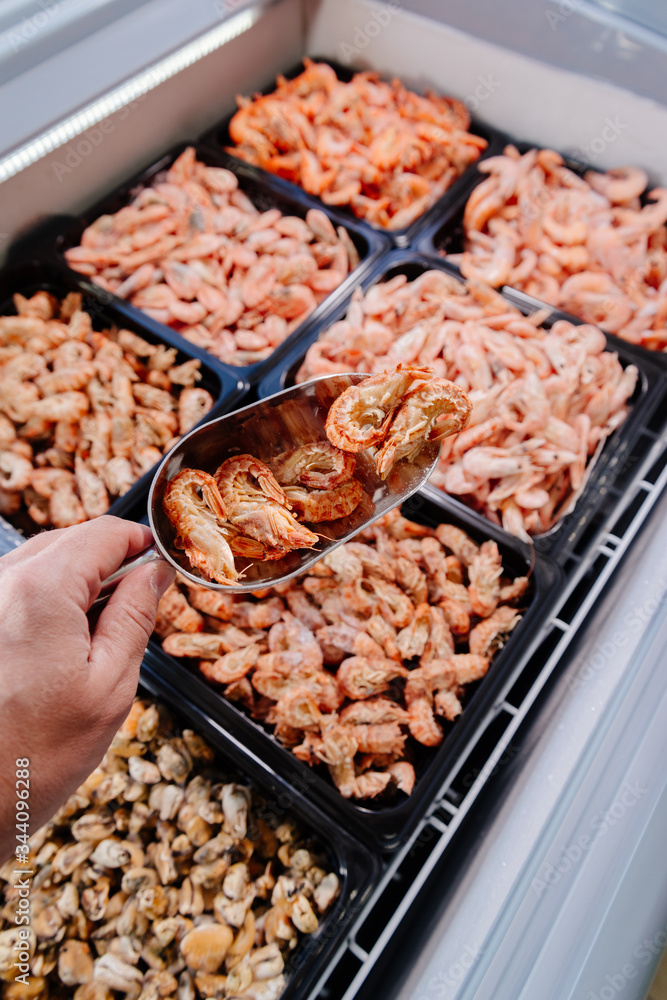 Man holds scoop with shrimp in supermarket. Frozen prawns in a ...