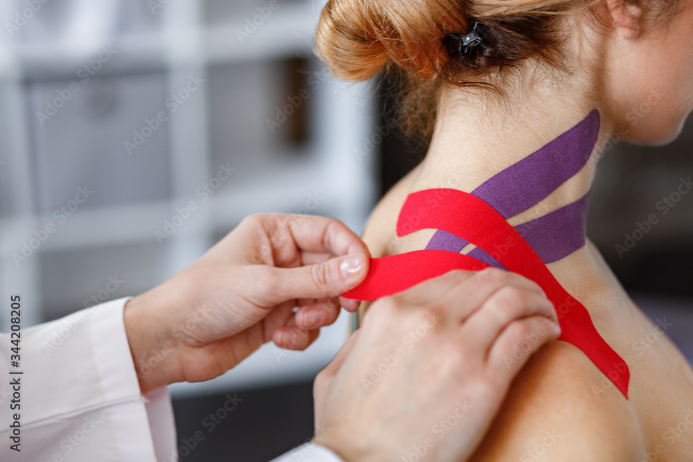 Kinesiology taping. Physical therapist applying kinesiology tape to patient neck. Therapist ...