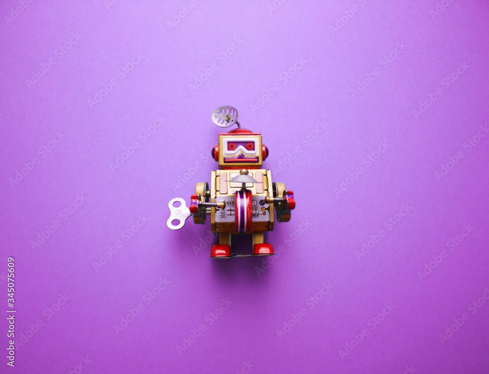 Vintage clockwork metal toy robot on the purple background. Retro toys ...