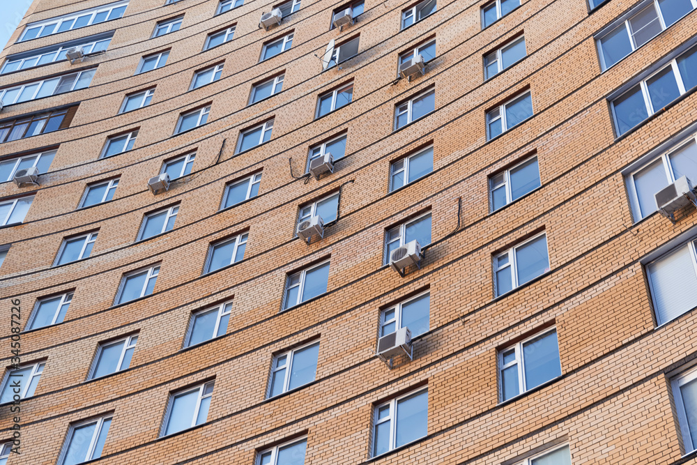 The curved wall of a brick house with many Windows and several air ...