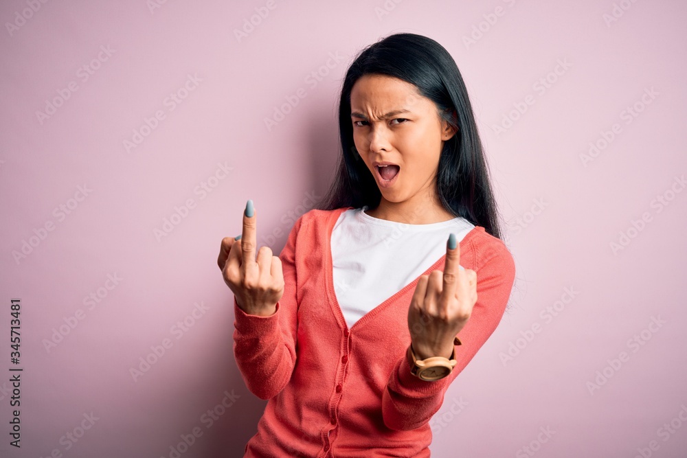 Young beautiful chinese woman wearing casual sweater over isolated pink ...