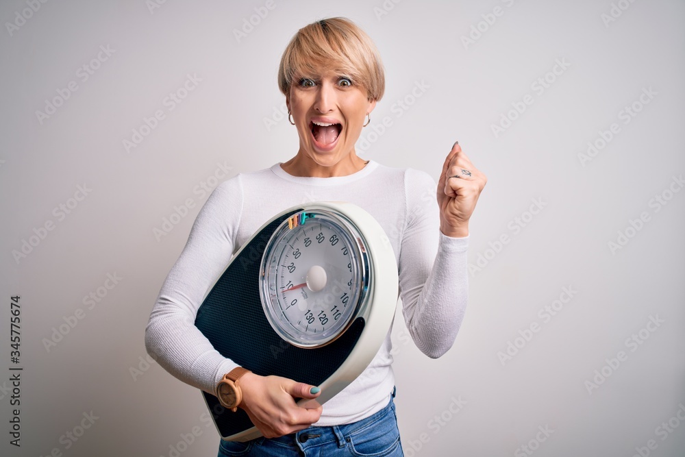 Young blonde woman with short hair holding scale for healthy weight and ...