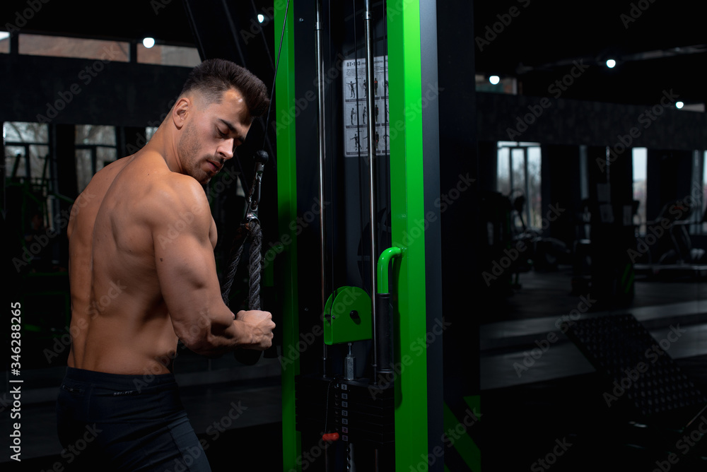 male athlete shows near the green simulator how to perform the exercise ...