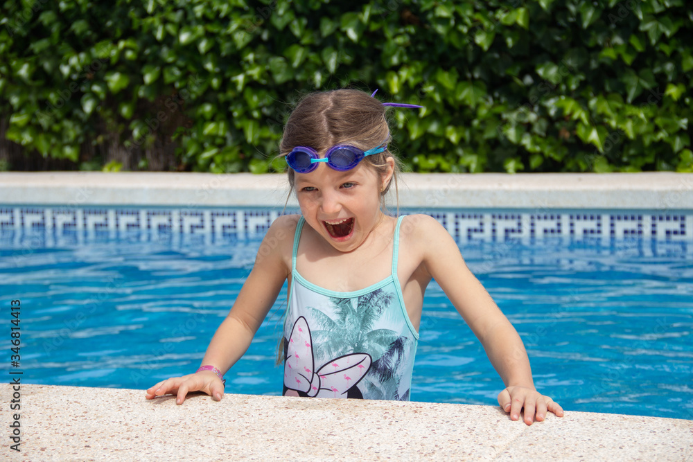 cute blonde girl in a swimsuit with violet blue glasses in the pool ...