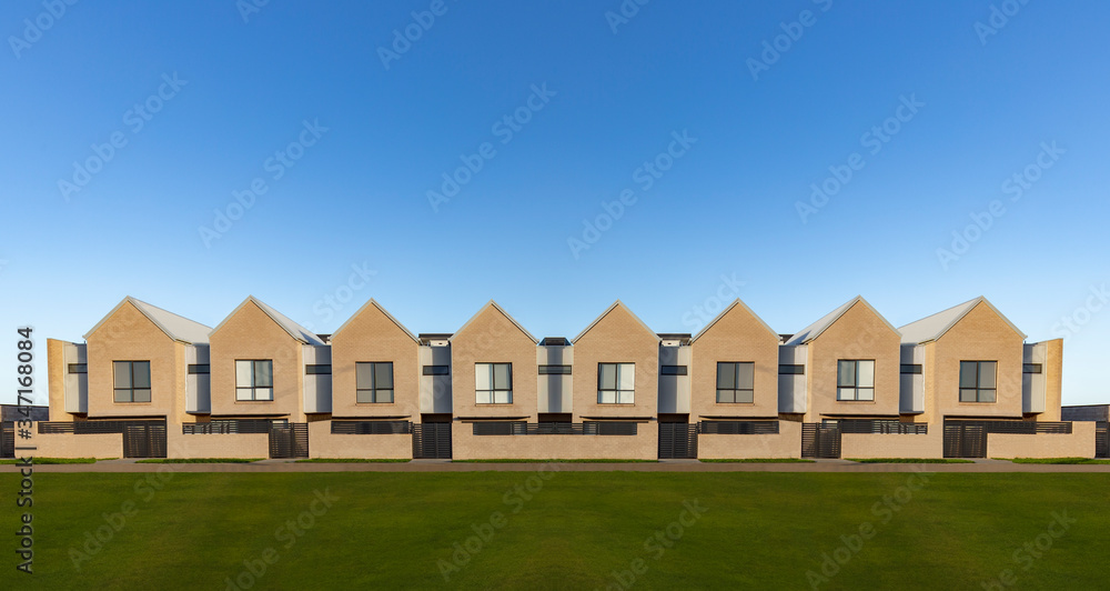 Front view of a symmetrical row of modern two storey townhouses along a ...