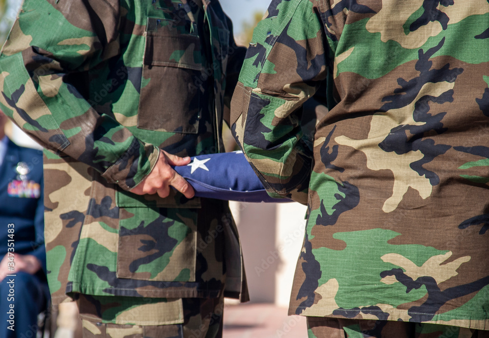American Flag in the process of being folded by soldiers dressed in ...