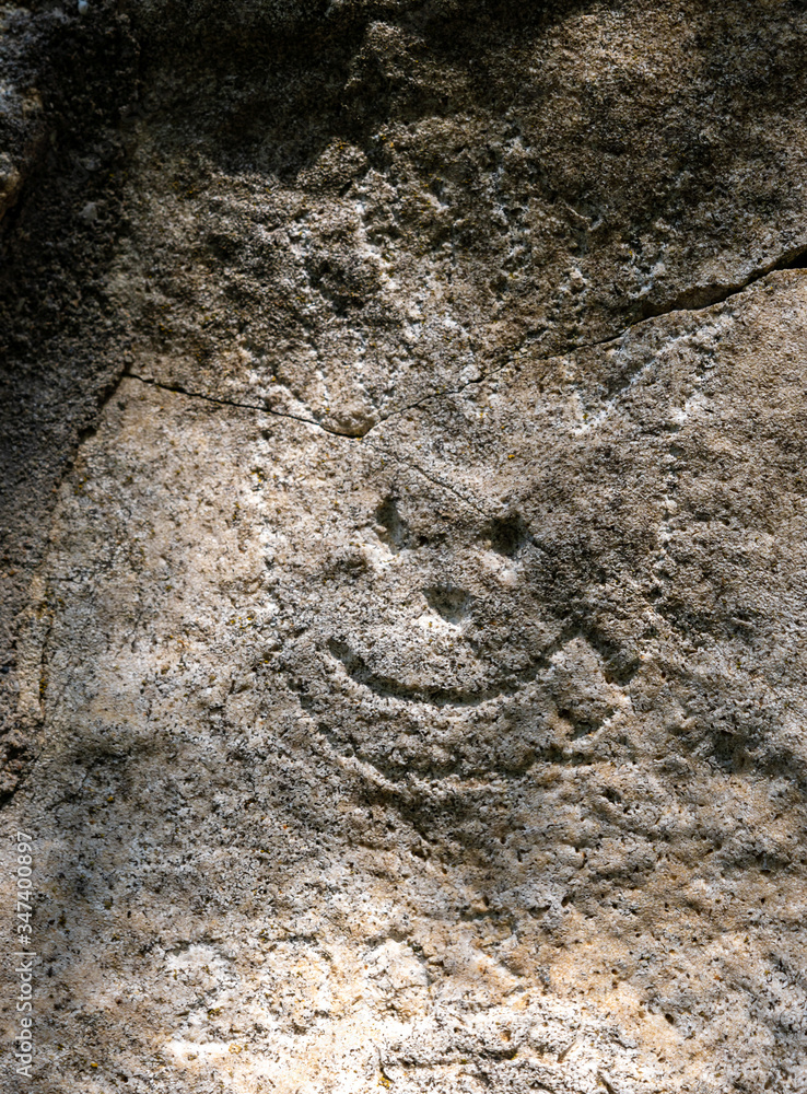 Stone with a scratch out smile. On a stone is an image of a happy face ...