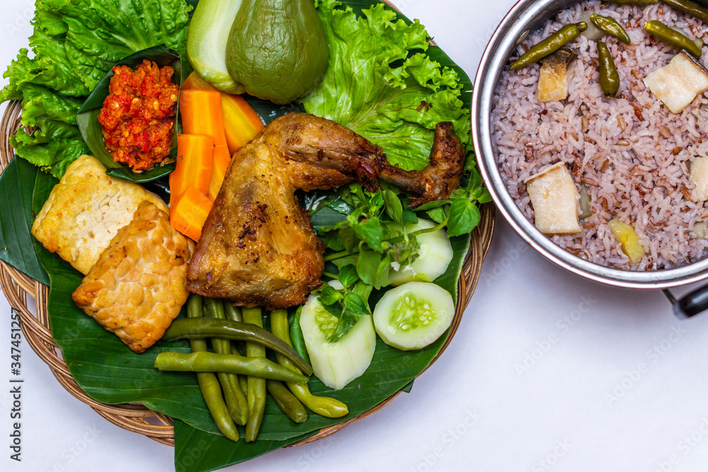 Indonesian traditional food nasi liwet with fried chicken, tahu, sambal ...
