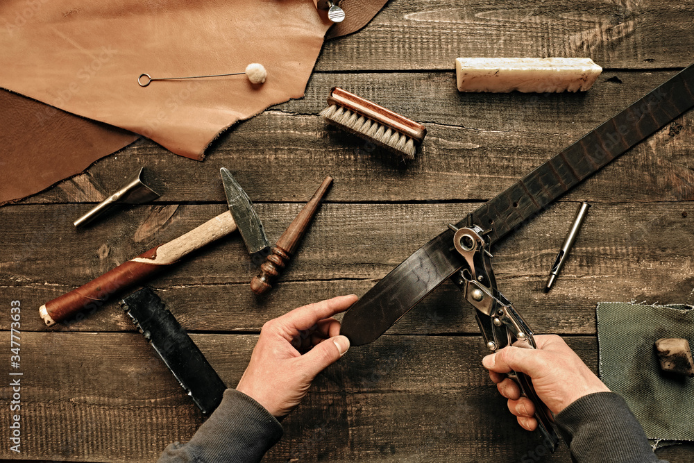 Working process of the leather belt in leather workshop. Man holding ...