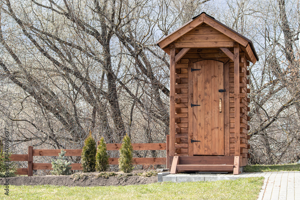 Wooden rustic toilet on early spring trees background. Modern rural ...
