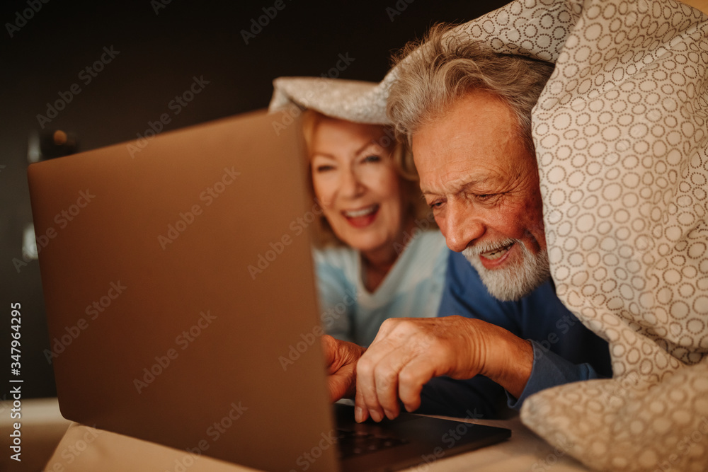 Close photo of elderly men typing on laptop keyboard while lying in bed ...