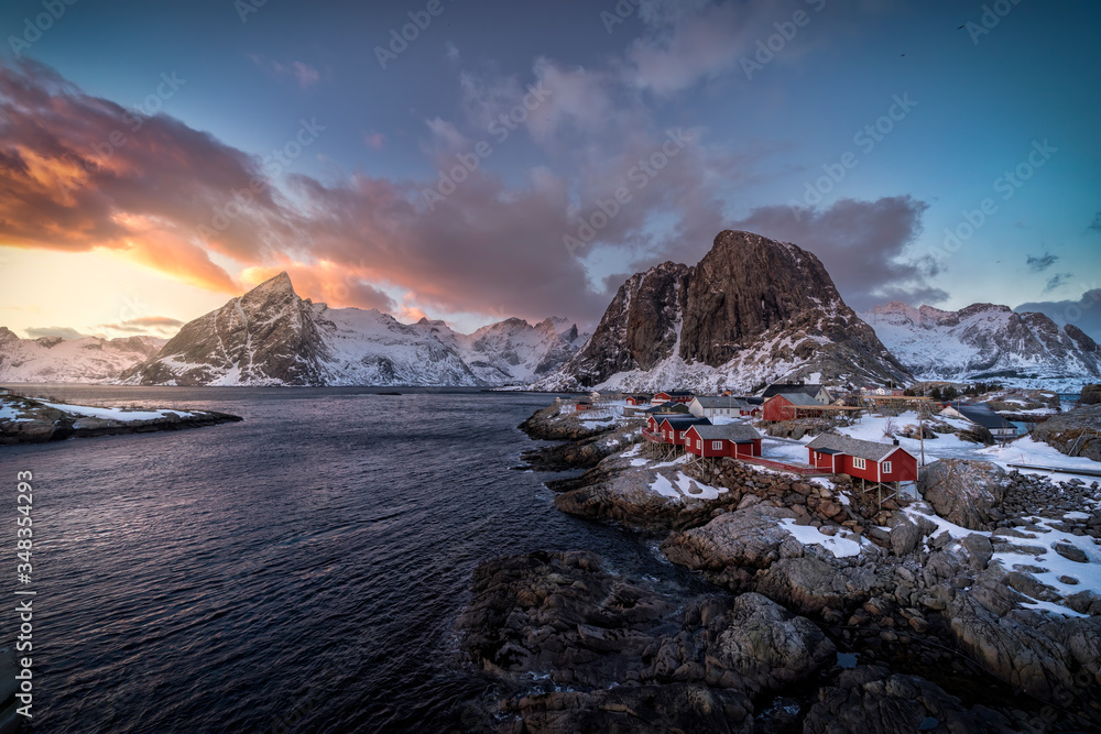Village with red cabins by the sea with mountains in the background ...