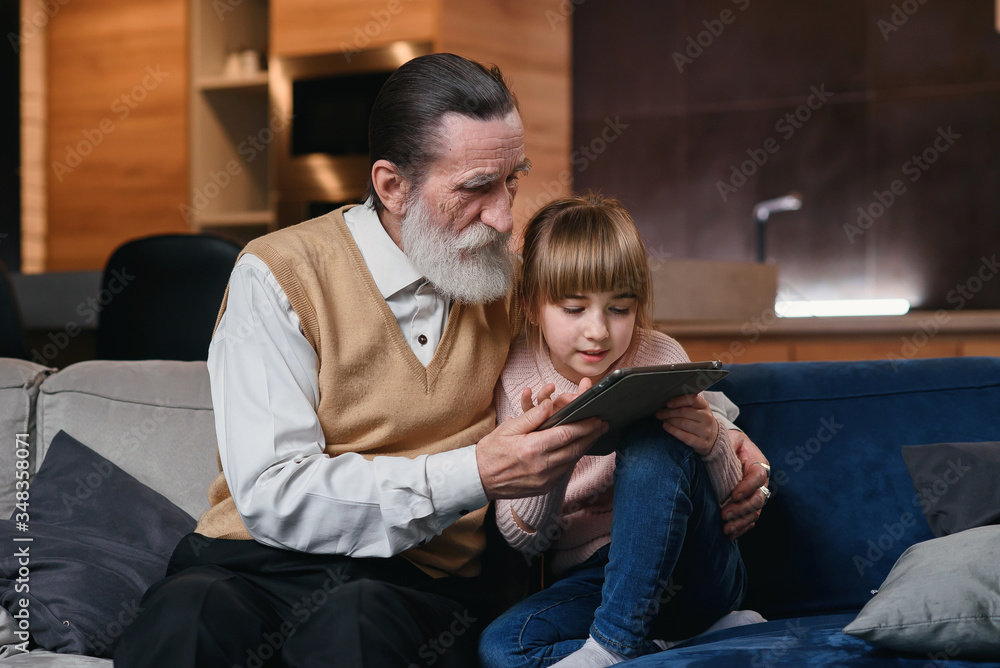 Grandpa with his granddaughter using tablet pc at cozy home. Little ...