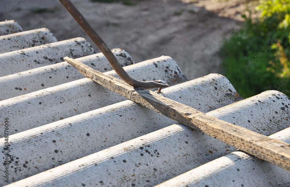 Residential asbestos removal: a building contractor is pulling nails out of a dangerous ...