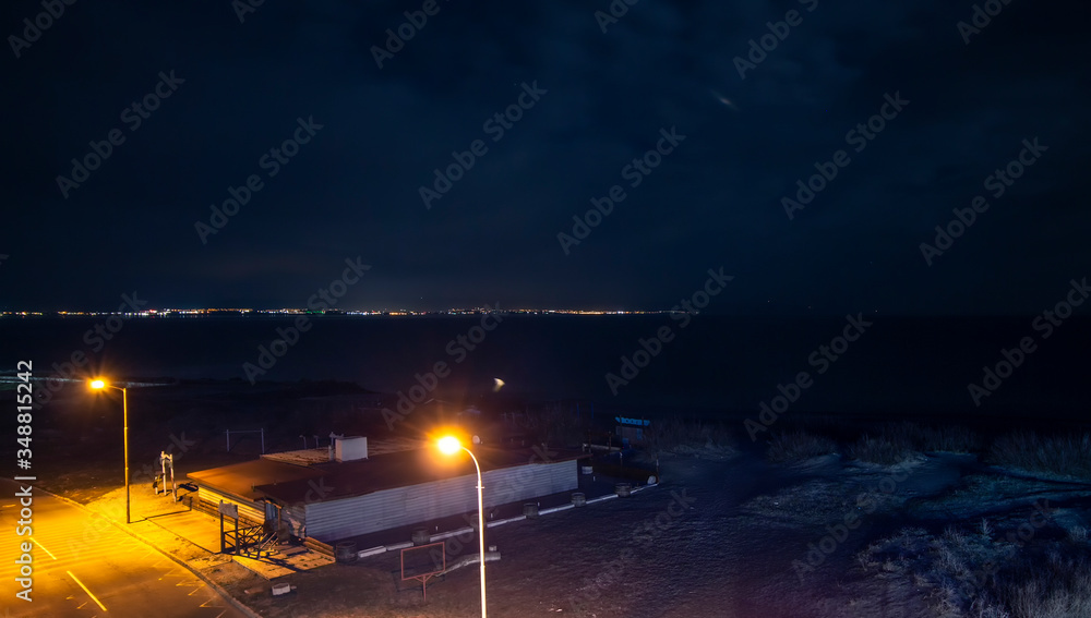 Night scene on the beach. With street lamps and city lights across the ...
