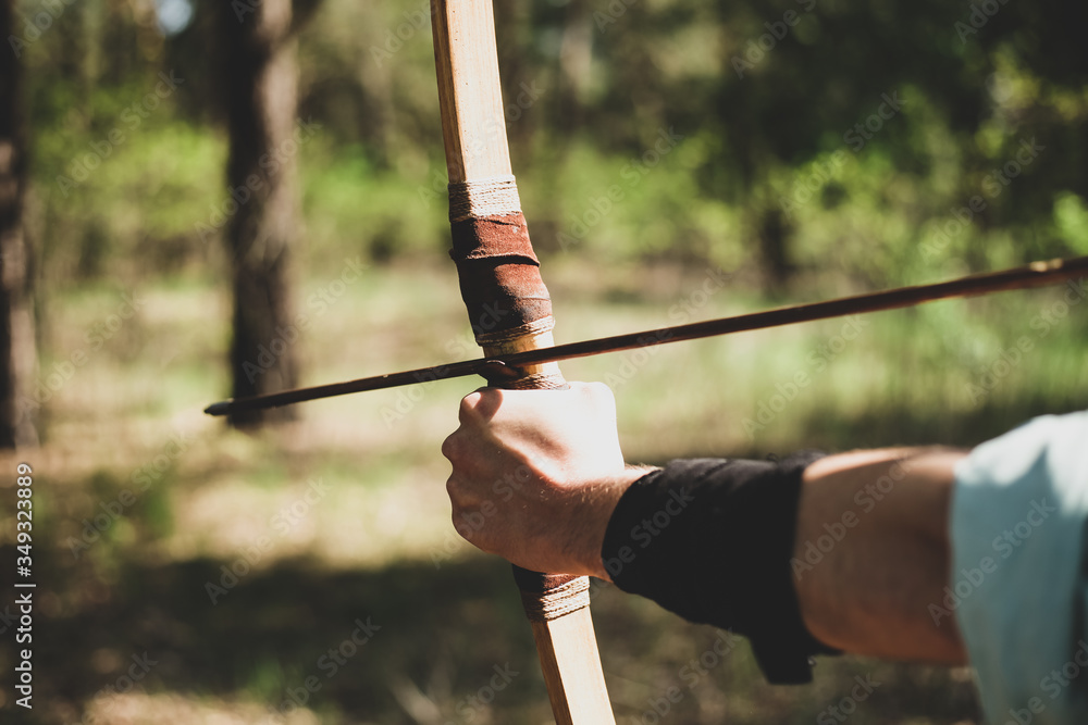 A man shoots a bow in the open air. The near foreshortening. An arrow ...