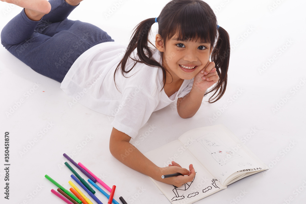 Cute little girl doing homework, reading a book, coloring pages ...