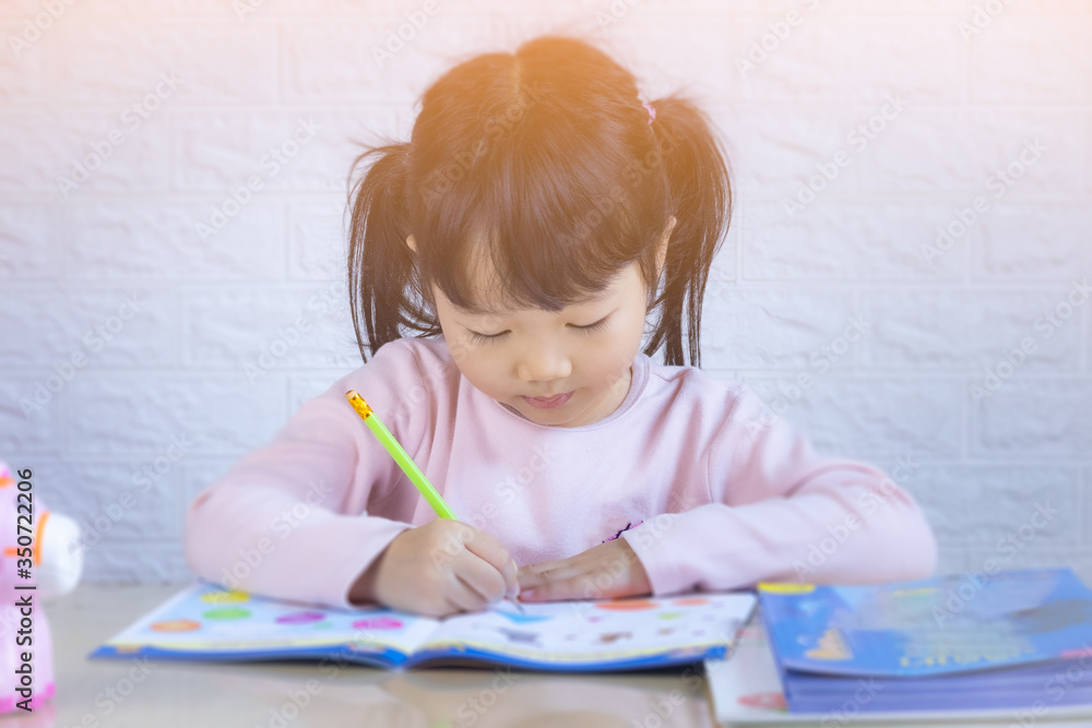 Photo Stock Cute little girl doing homework, reading a book, coloring ...