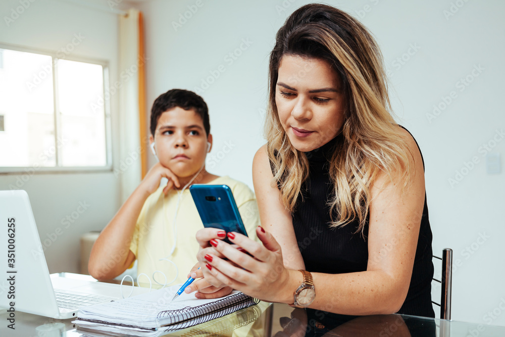 Mother using cell phone ignoring her son while he is doing homework ...