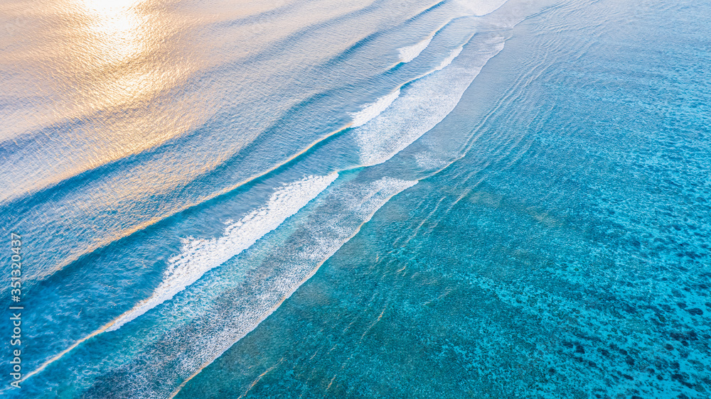 Aerial view of calm waves, breaking at the reef of the local ...
