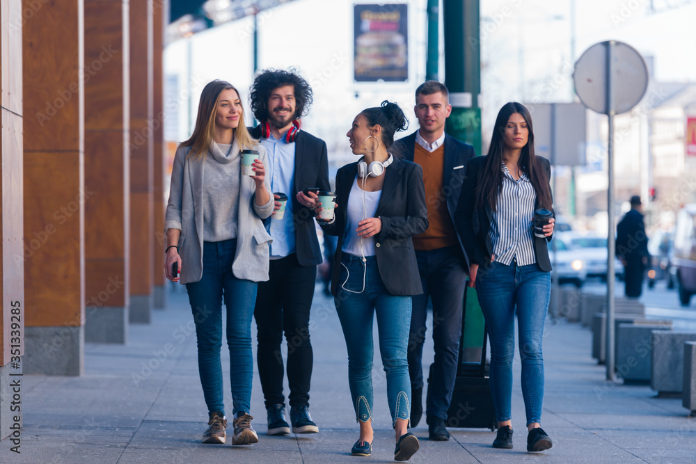 Group of diverse coworkers walking together, smiling and expressing a ...