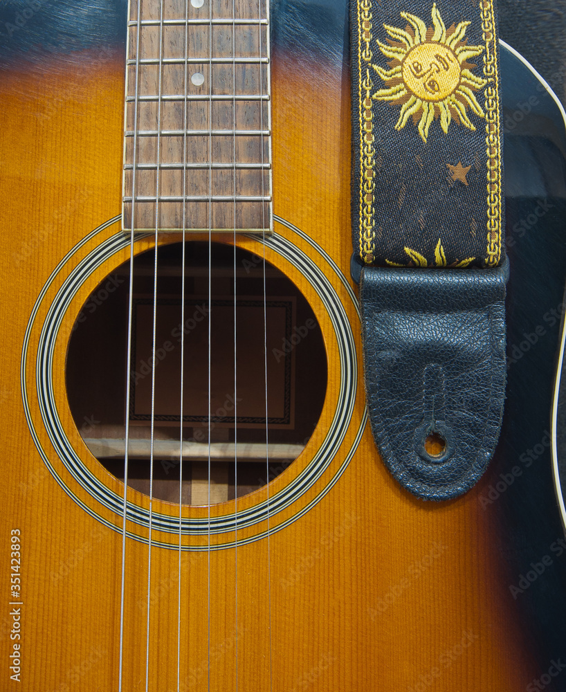 yellow classic six-string guitar with a leather strap depicting the sun ...