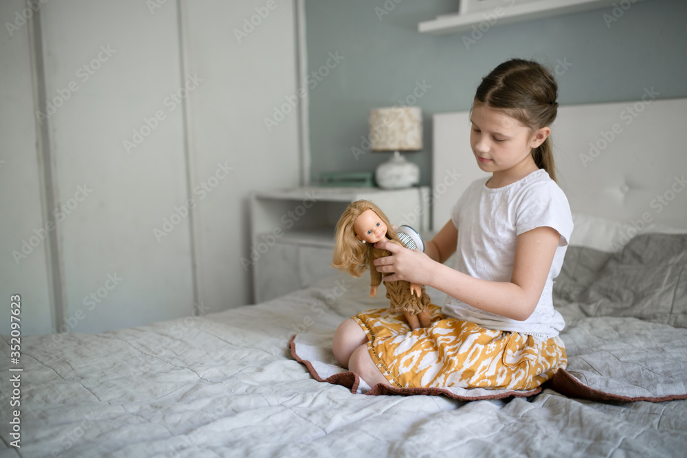 Caucasian girl combing a doll with long hair, a girl playing dolls ...