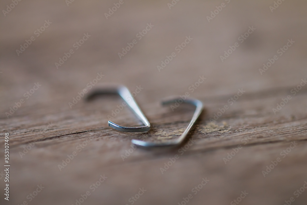 The two staples that have been bent are placed on a brown wooden floor ...