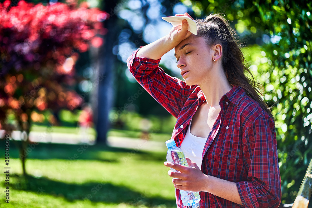 Young tired woman suffering from hot weather outdoors in a summer day ...