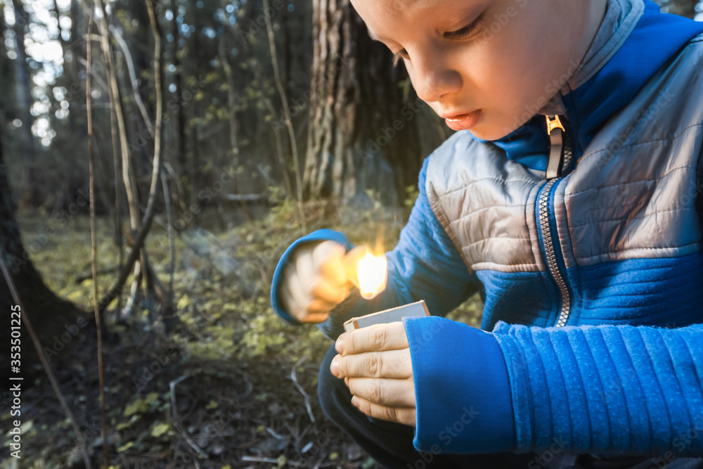 Foto de Stock Little naughty boy sets fire to match in forest. Danger ...