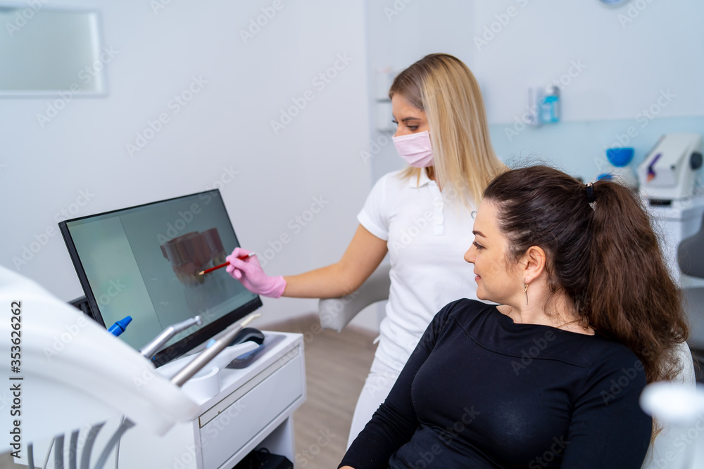 Dentist shows a patient x-ray of teeth on monitor. Explains methods of ...