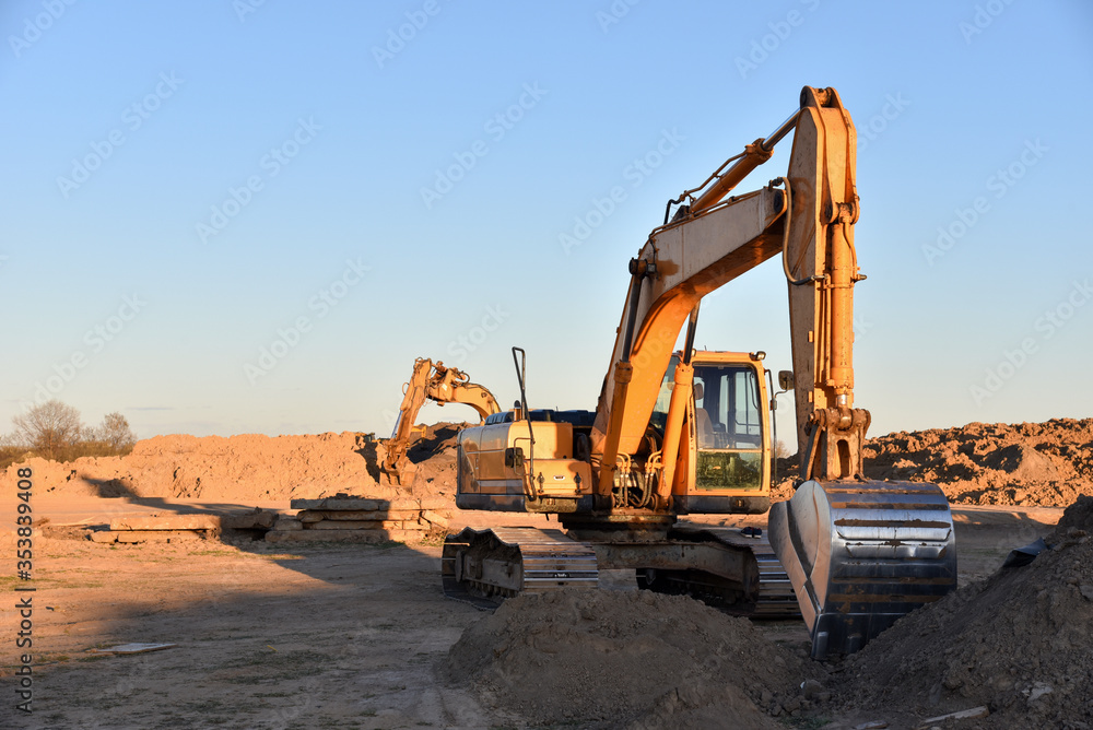 Excavators during earthmoving at construction site. Backhoe dig ground ...