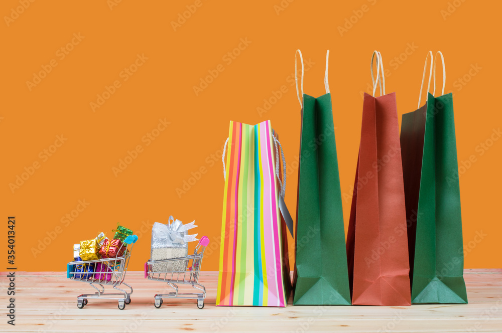 Paper shopping bags and trolley carts with full of gifts on the wooden ...