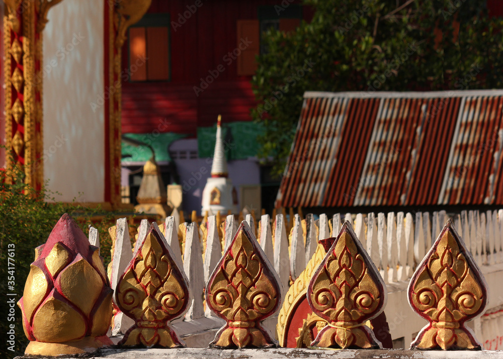 Tip of a stony and golden painted stupa in front of a religious wooden ...