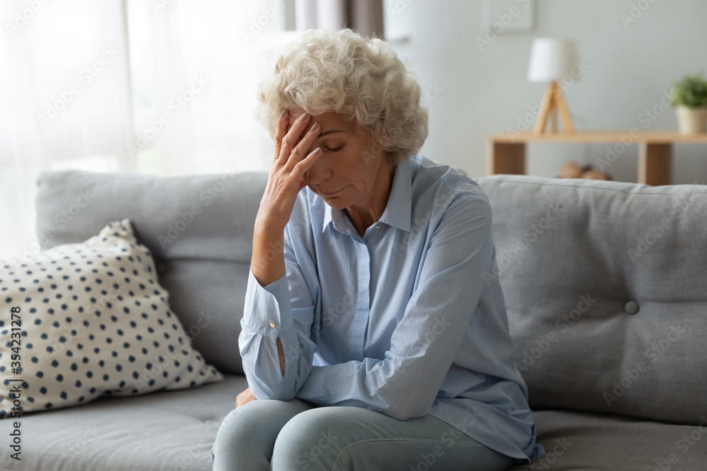 Sad elderly woman cover face with hand sit on couch lost in sad ...