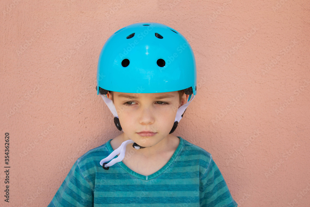 Sad boy in a Bicycle helmet for safety on a beige background. Lost the ...