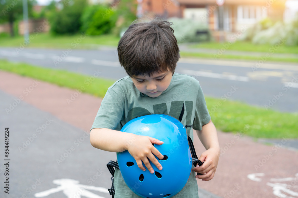 Emotional Portrait of kid boy with upset face holding safety helmet ...