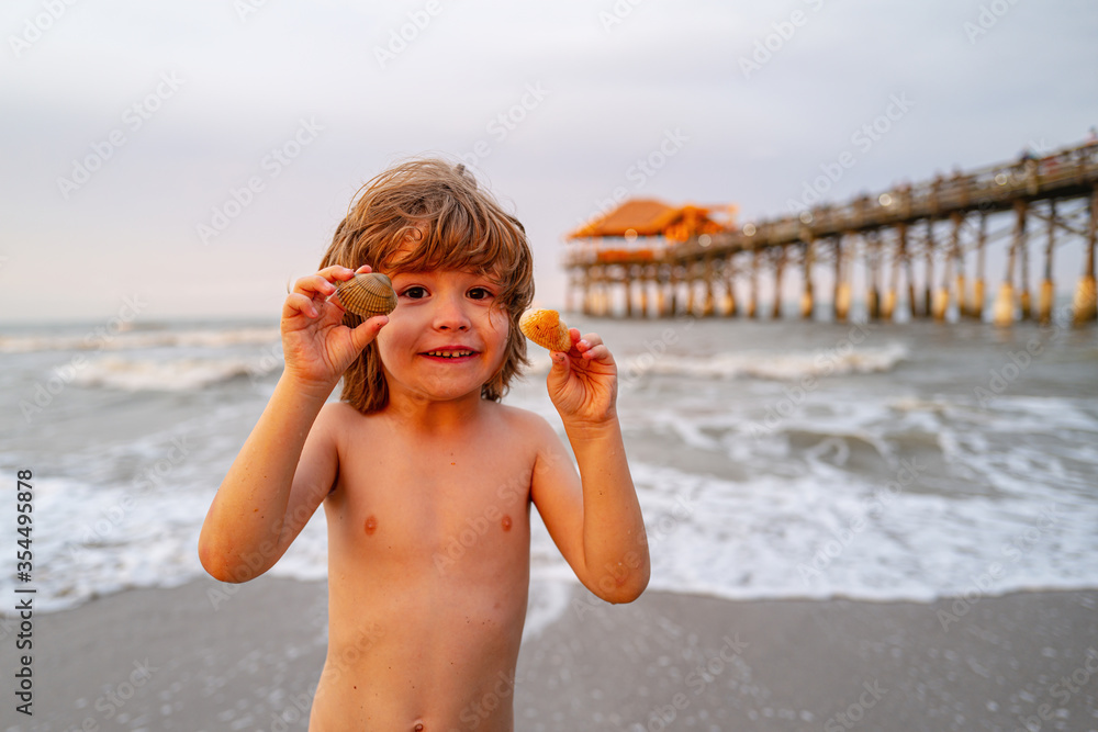 Cute, happy child holding shell at the beach. Cute little boy at ...
