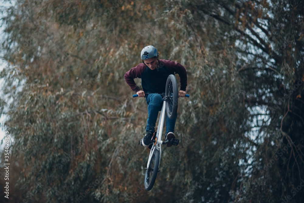 Professional young sportsman cyclist with bmx bike making acrobatic ...