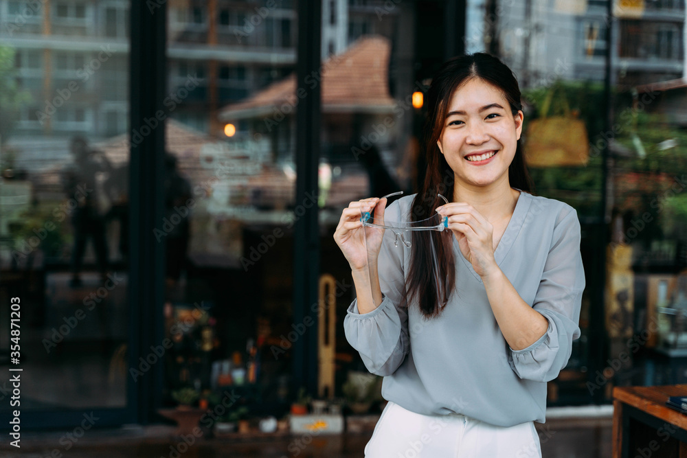 Portrait of Asian woman taking off and showing a face shield to prevent ...