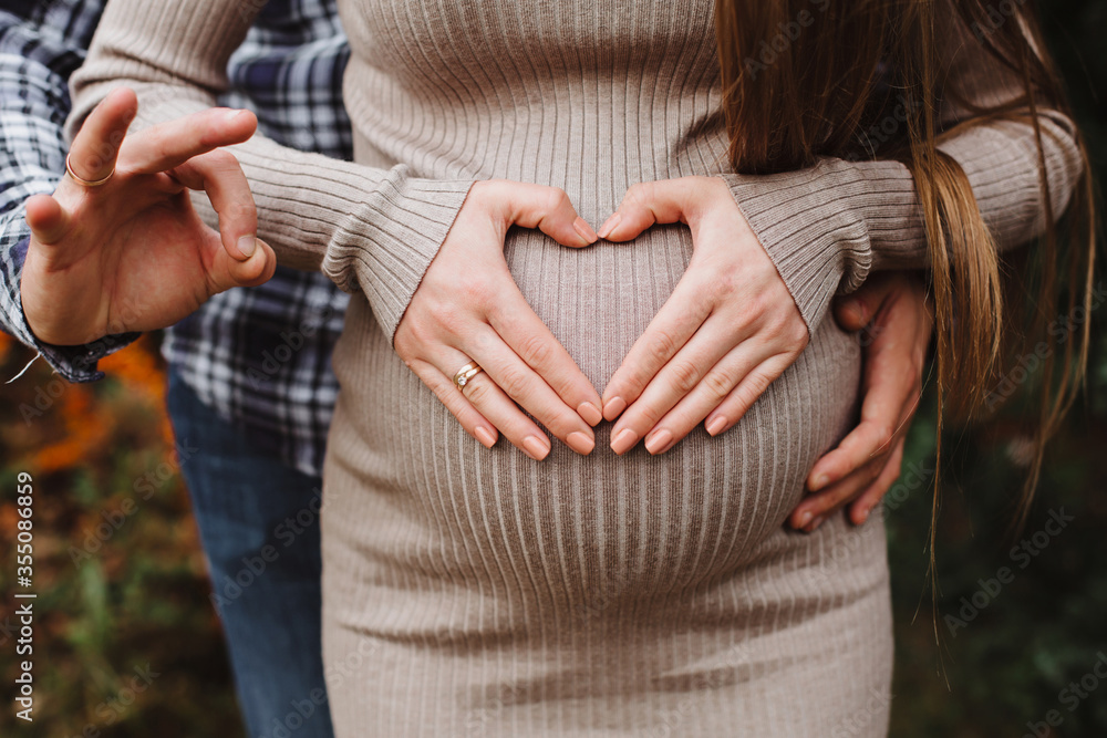 Heart of hands by multiethnic couple on pregnant belly. Man holding ...
