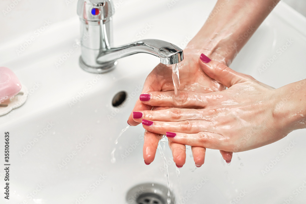 Young woman washing her hands under water tap faucet with soap. Detail ...